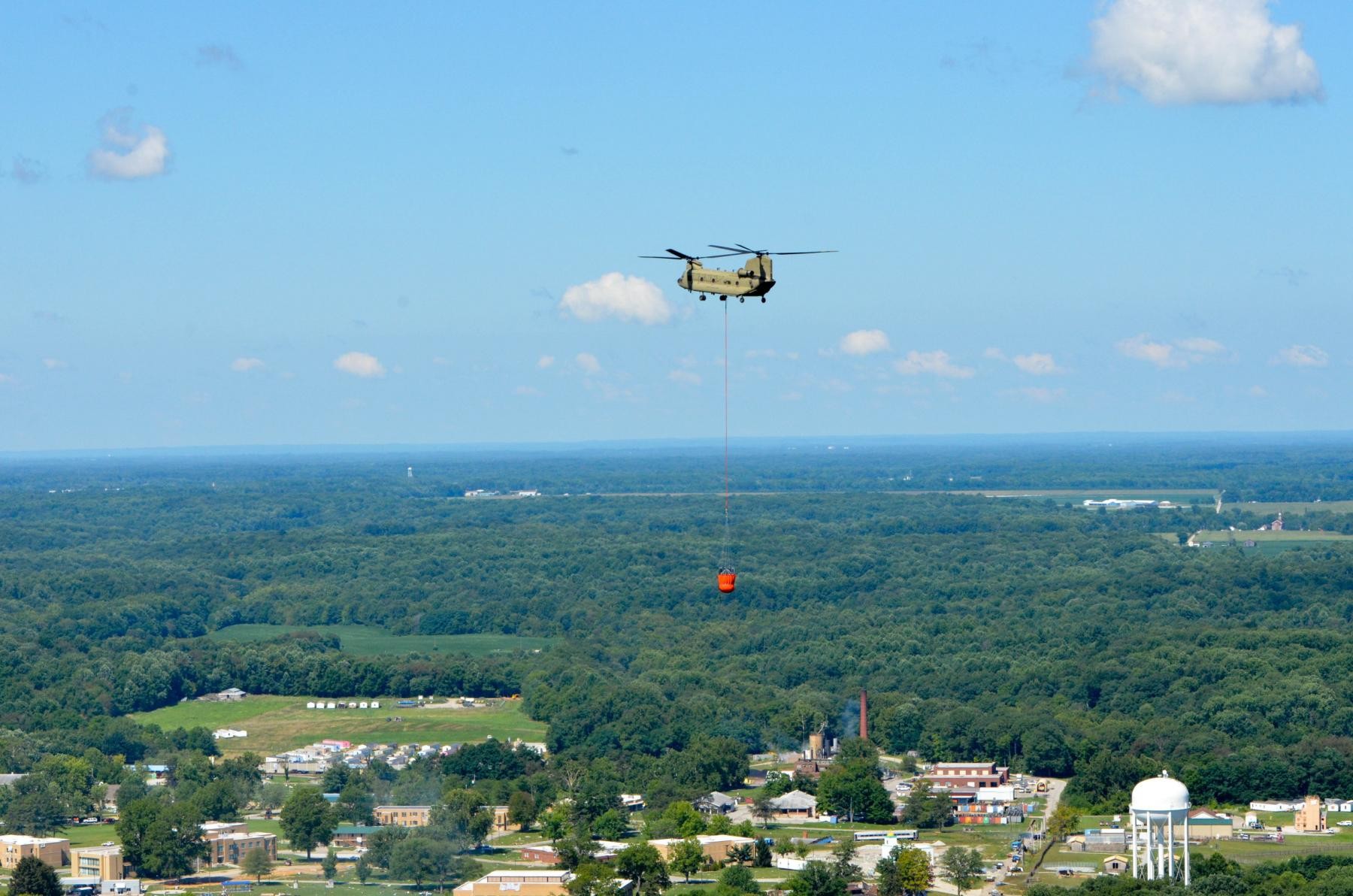 A CH-47 Chinook helicopter sling loads a Bambi Bucket over Muscatatuck ...
